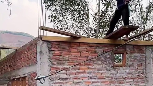 建厨房的工人正在封厨房的顶,建房子的工人正在绑扎圈梁钢筋