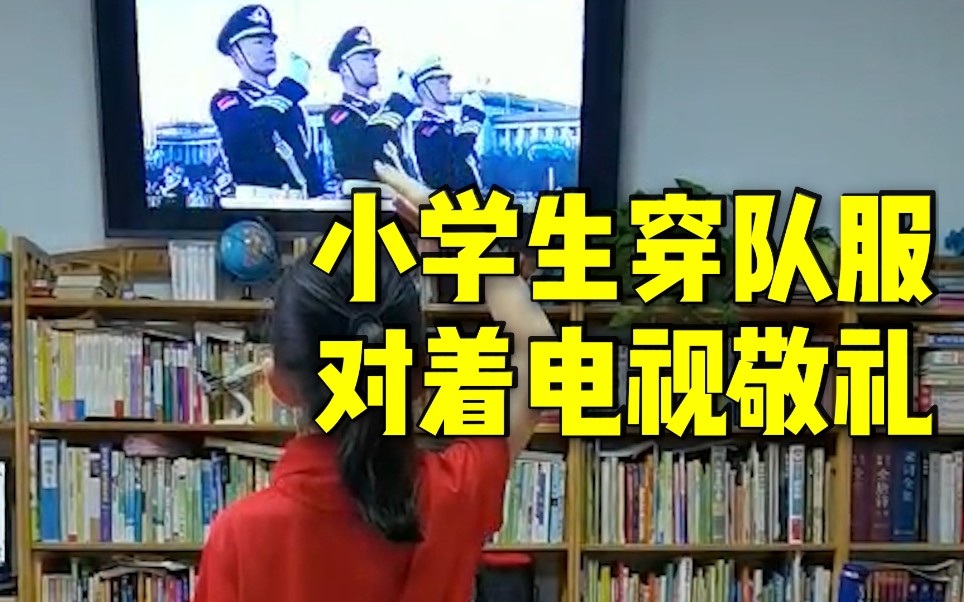 小学生穿队服对着电视机敬礼