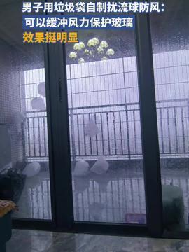 ...台风"麦德姆"来袭狂风肆虐,一名男子用垃圾袋自制"扰流球"防风,保护...