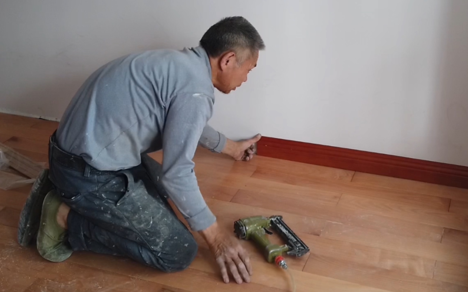 安装实木踢脚线,是实木地板安装的最后阶段,赵师傅使用小型空压机...