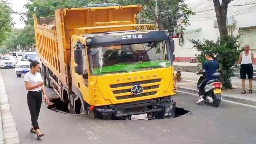 河南郑州:街头一渣土车趴窝 路面塌陷十多平方深坑