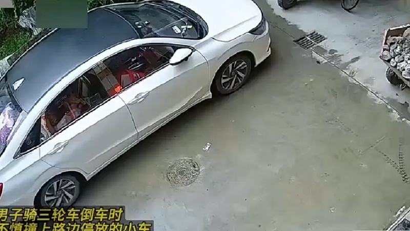 男人骑三轮车倒车时不慎撞上路边停放的小车