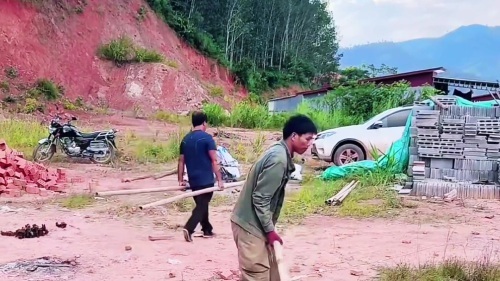 勤快的三哥正在挑选直溜一点的钢管抱到后墙递送上去搭设外脚手架