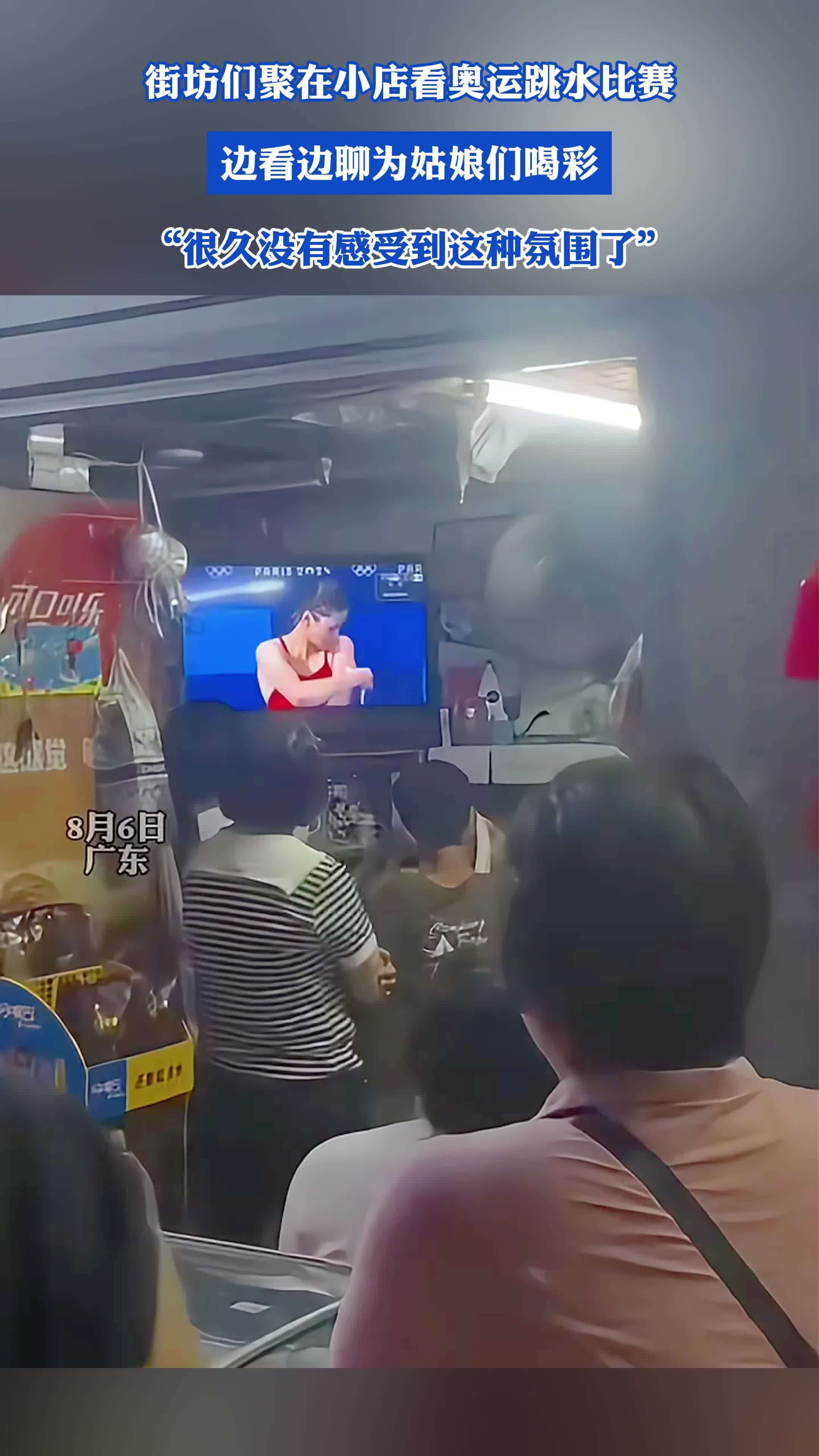 街坊们聚在小店看奥运跳水比赛,边看边聊为姑娘们喝彩