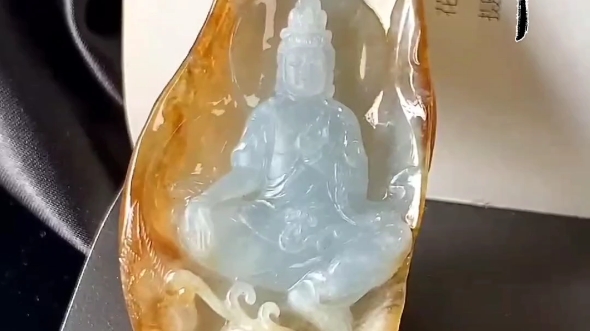 黄翡料子色泽明亮,采用俏色巧雕工艺,白肉部分琢观音自在坐,面容温和...