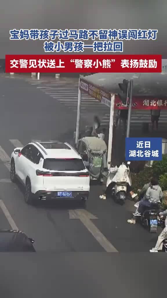 宝妈带孩子过马路误闯红灯被小男孩一把拉回,交警送上小熊表扬