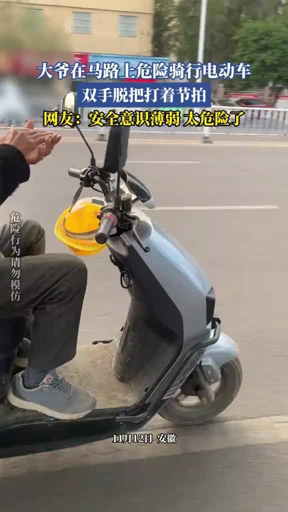 大爷在马路上危险骑行电动车,双手脱把打着节拍