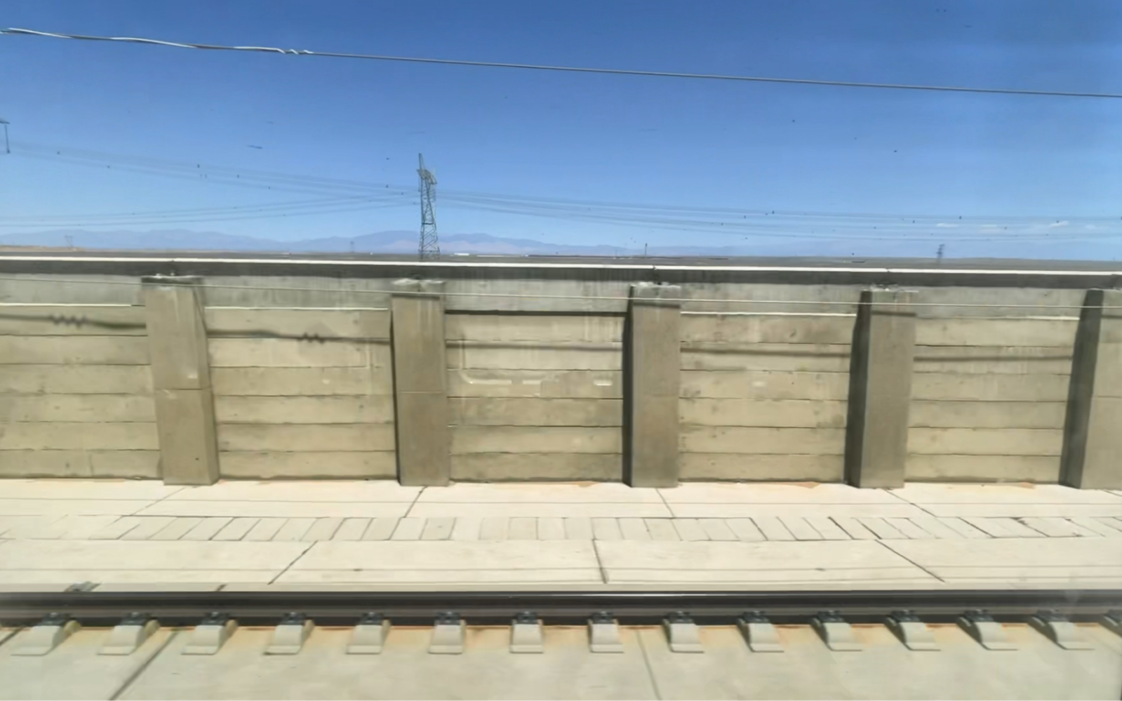 Z69次列车通过沙漠风沙带区域,铁路两侧有水泥挡墙防风沙侵蚀。