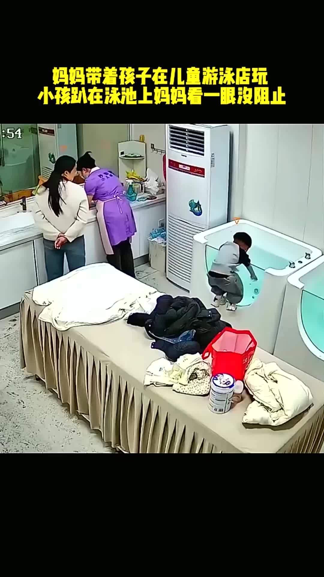 妈妈带着孩子在儿童游泳店玩,小孩趴在泳池上妈妈看一眼没阻止