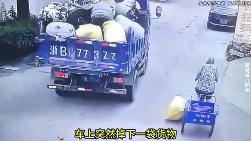 货车上掉下来一袋货物,刚好滚在三轮车下面,车子就这样翻车了