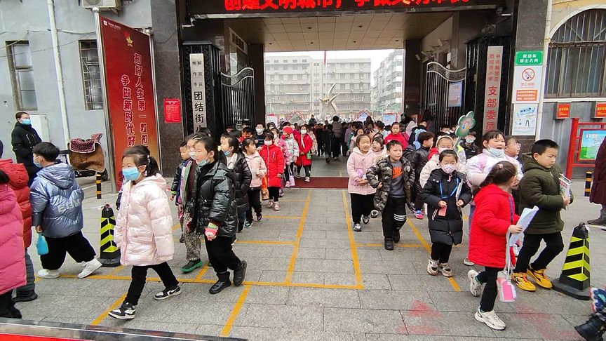 放学了,小学生有序唱着歌,走出了校门。