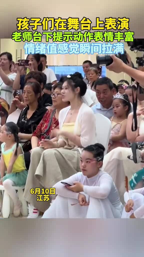 孩子们在舞台上表演,老师台下提示动作表情丰富