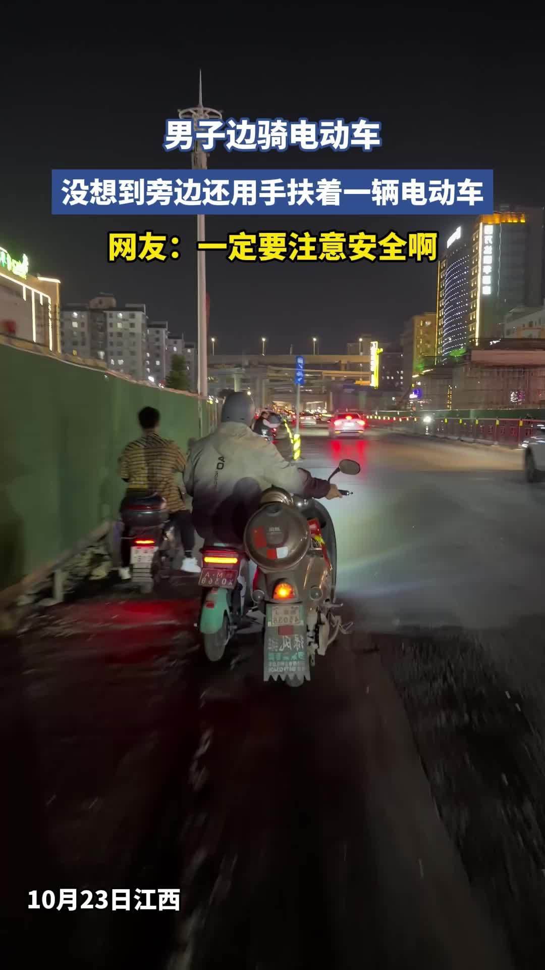 男子边骑电动车,没想到旁边还用手扶着一辆电动车