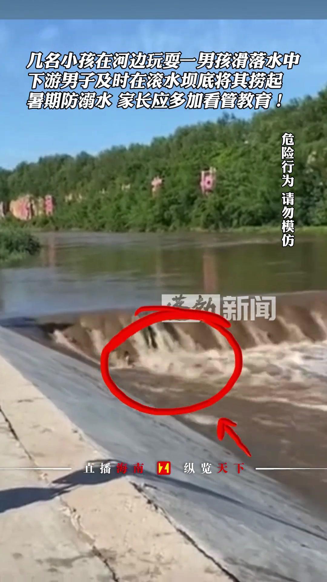 几名小孩在河边玩耍一男孩滑落水中,下游男子及时在滚水坝底将其捞...