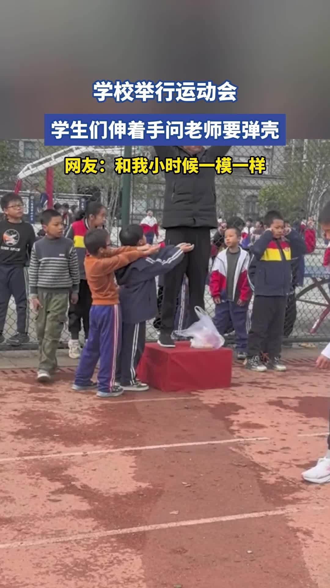 学校举行运动会,学生们伸着手问老师要弹壳