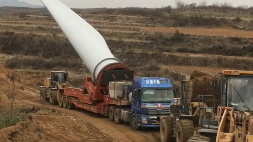 重型卡车运输长达60米风力发电桨叶,在狭窄的道路上艰难前行