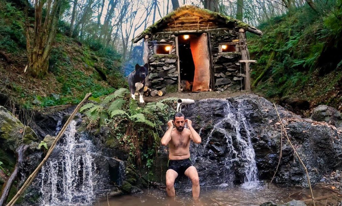 在森林深处建造一个丛林生存庇护所。用木头和石头建造的房子。冬季...