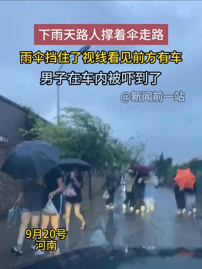 下雨天路人撑着伞走路,雨伞挡住了视线
